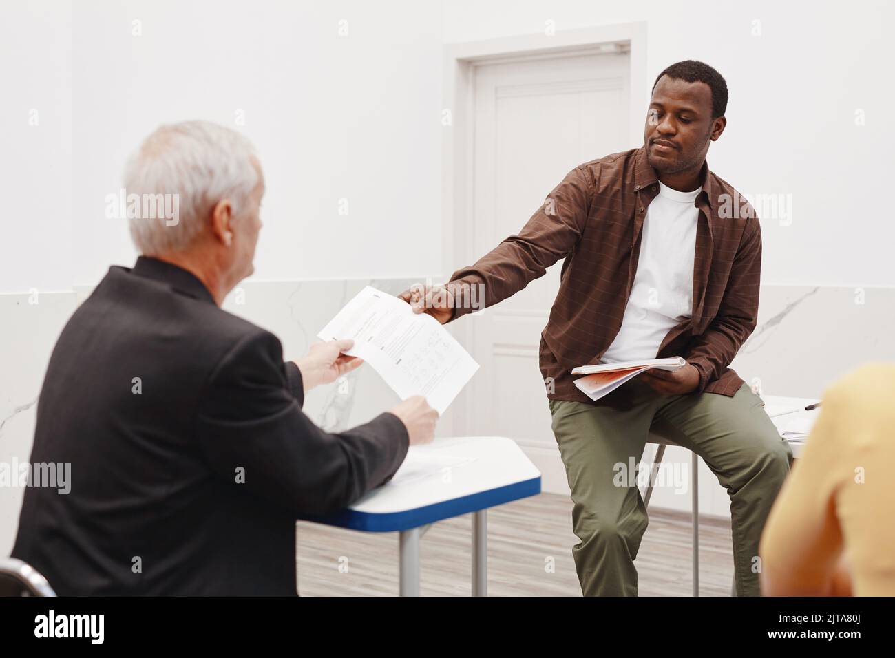 African teacher giving results of test to adult senior student during ...