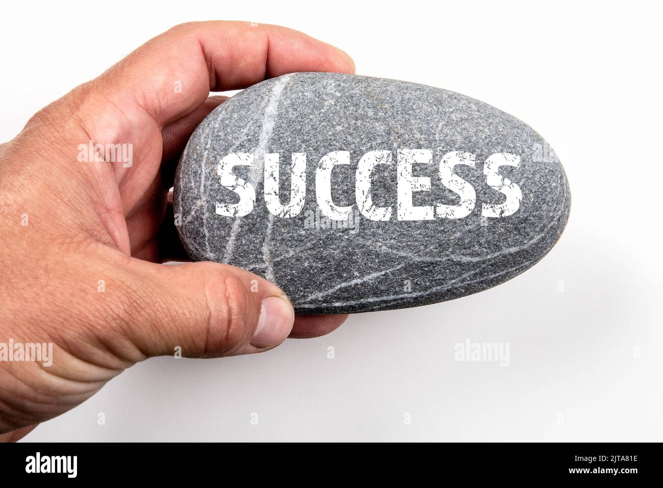 Success concept. Text on a gray stone in a man's hand. White background ...