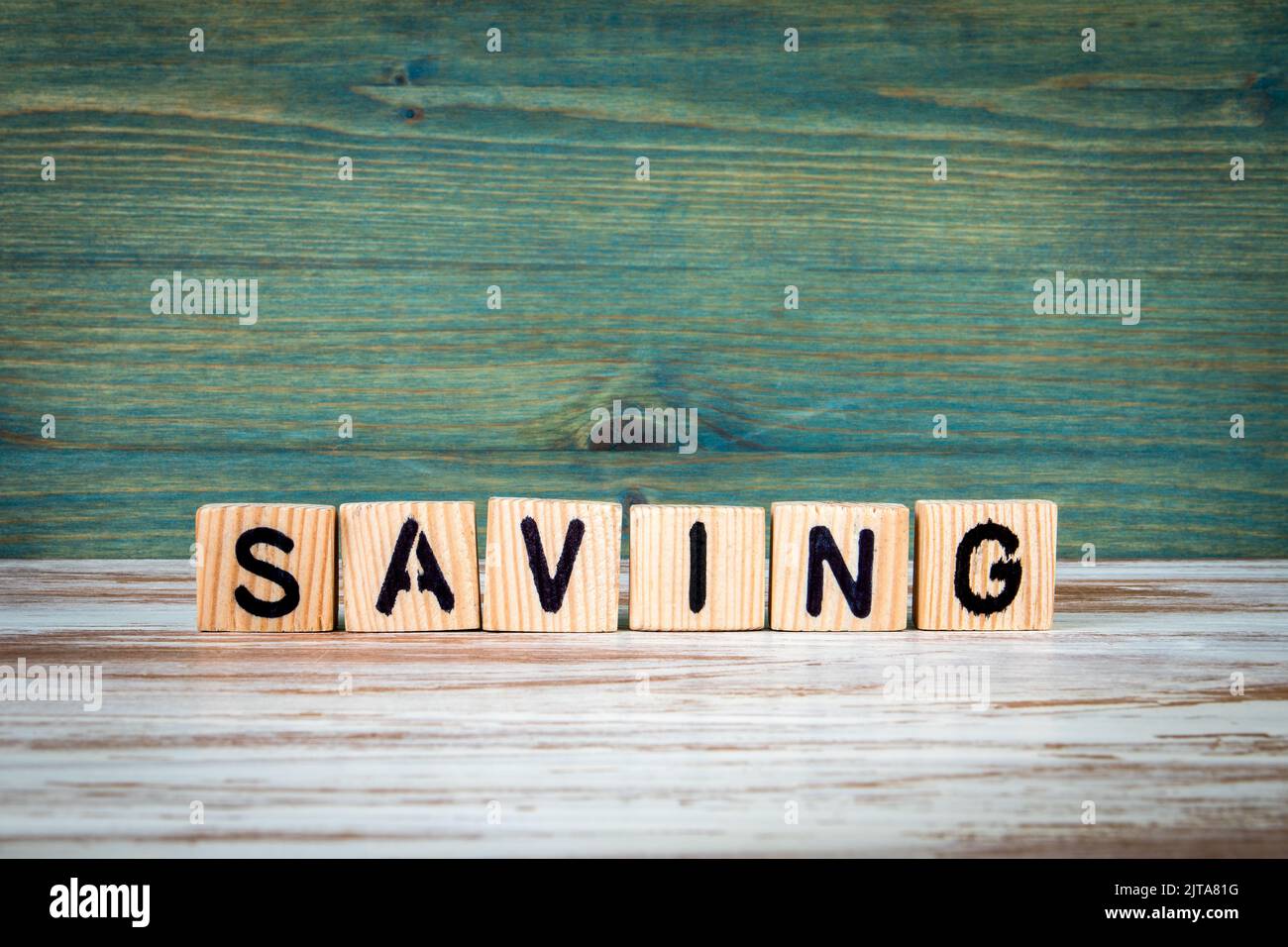 Saving. Text from wooden alphabet letters on green and white background ...