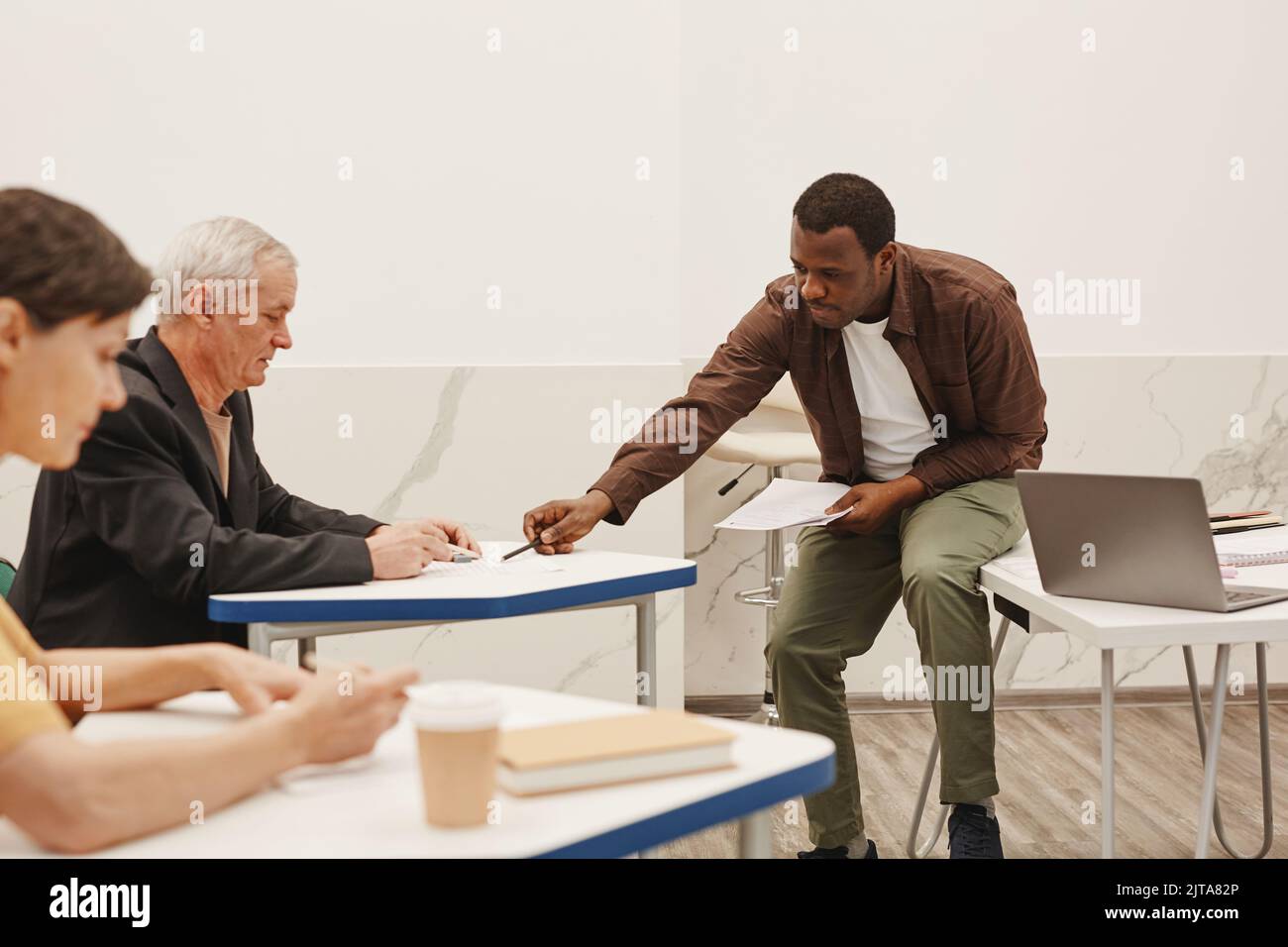 African teacher explaining how to write test to senior student during ...