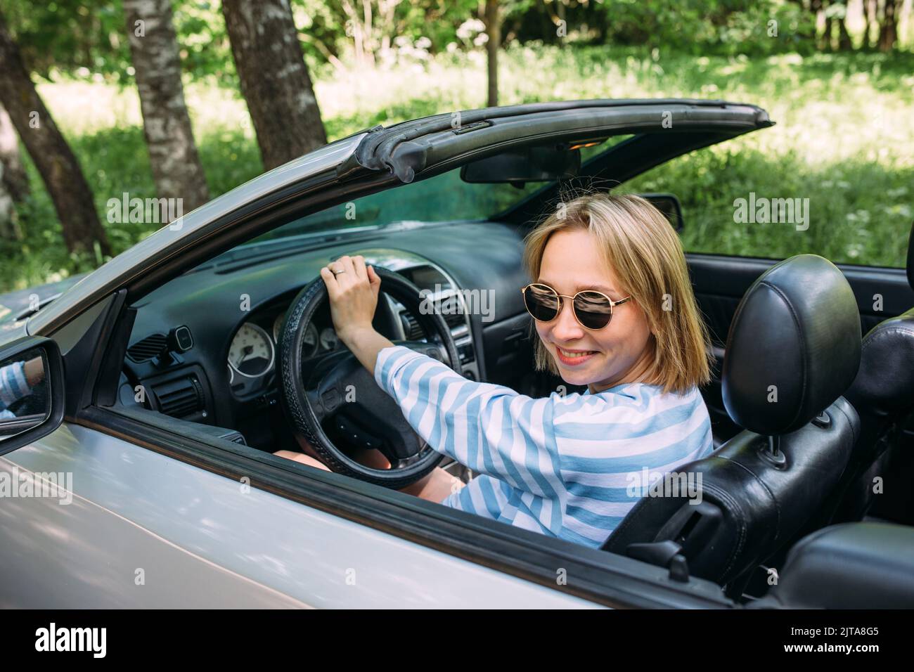 A woman is driving a convertible car. Summer road trip to nature Stock ...