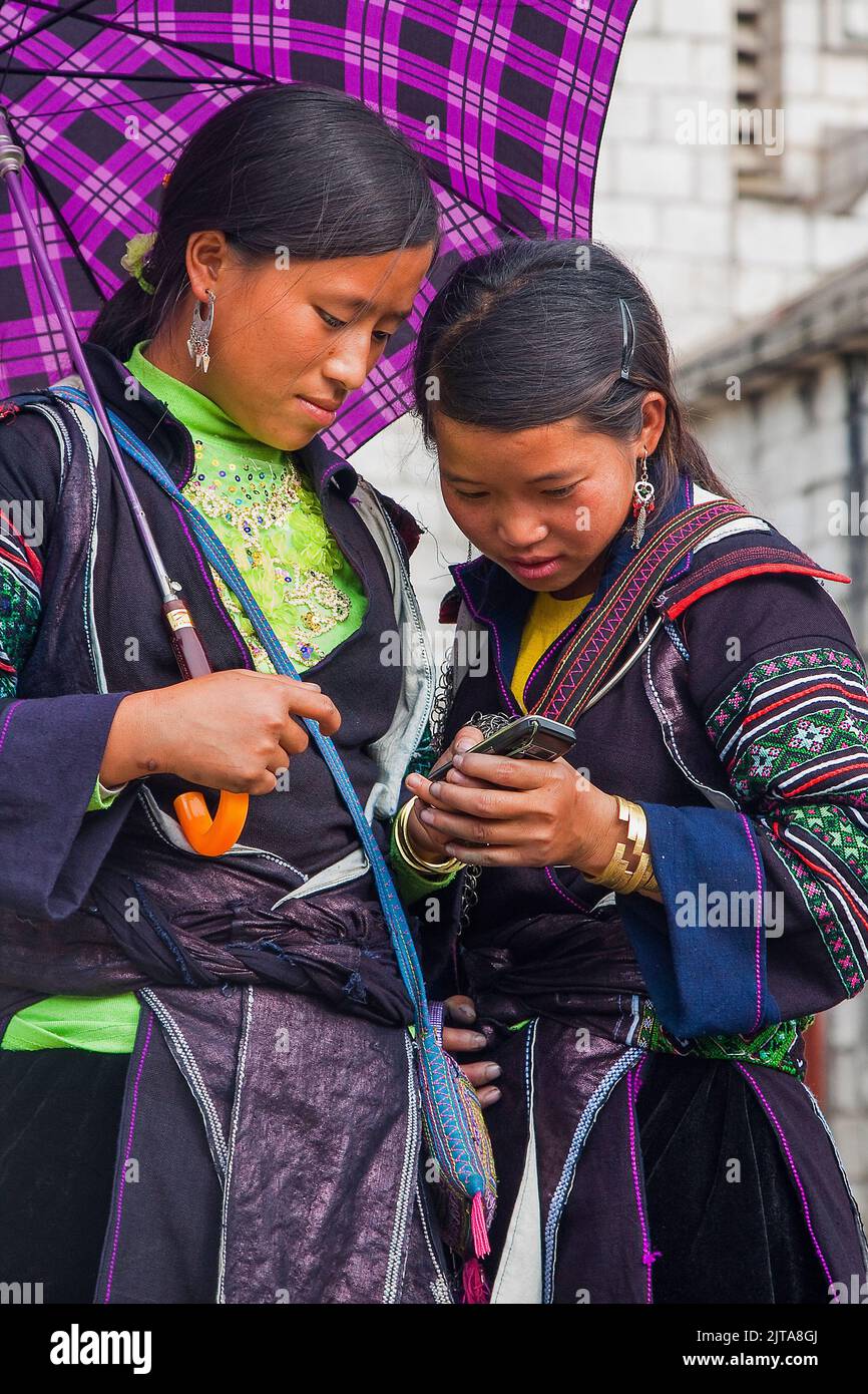 Vietnam, Sapa. Two Hmong girls talking and playing with their mobile ...