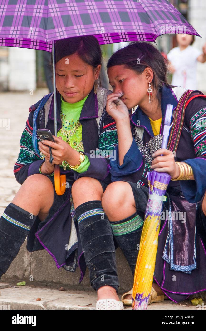 Vietnam, Sapa. Two Hmong girls talking and playing with their mobile ...