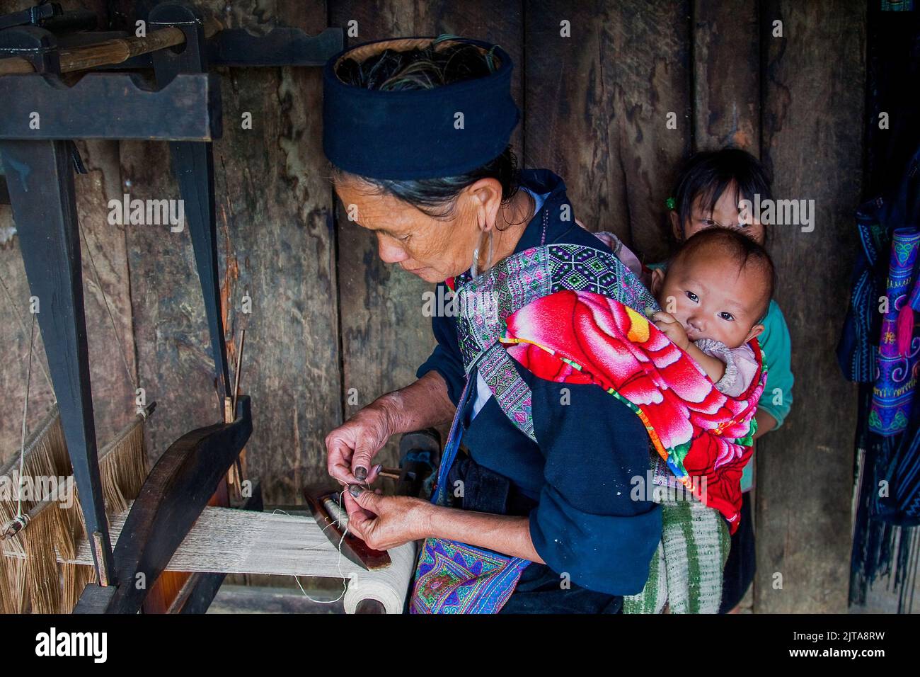 Vietnam, Black Hmong tribe woman is weaving hemp in a village near Sapa ...