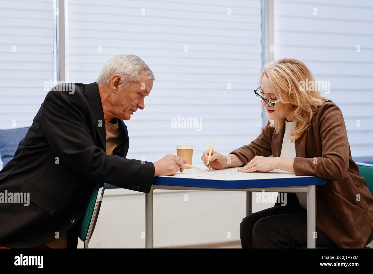 Senior man asking question to woman while she explaining him new topic ...