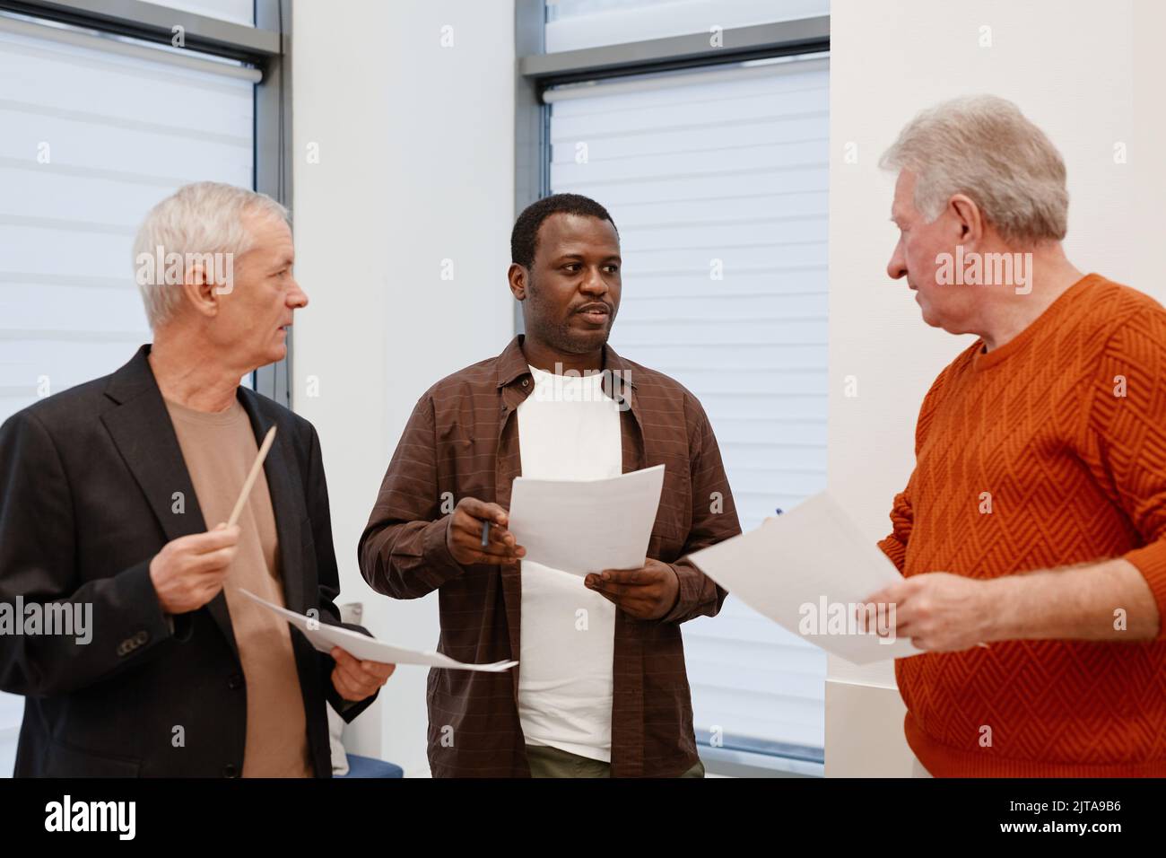 African teacher talking to his senior students after lesson, they ...