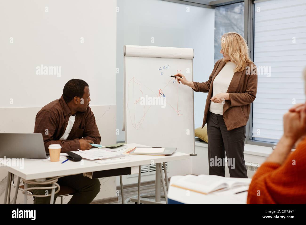 Mature woman making notes on flipchart to present her report for ...