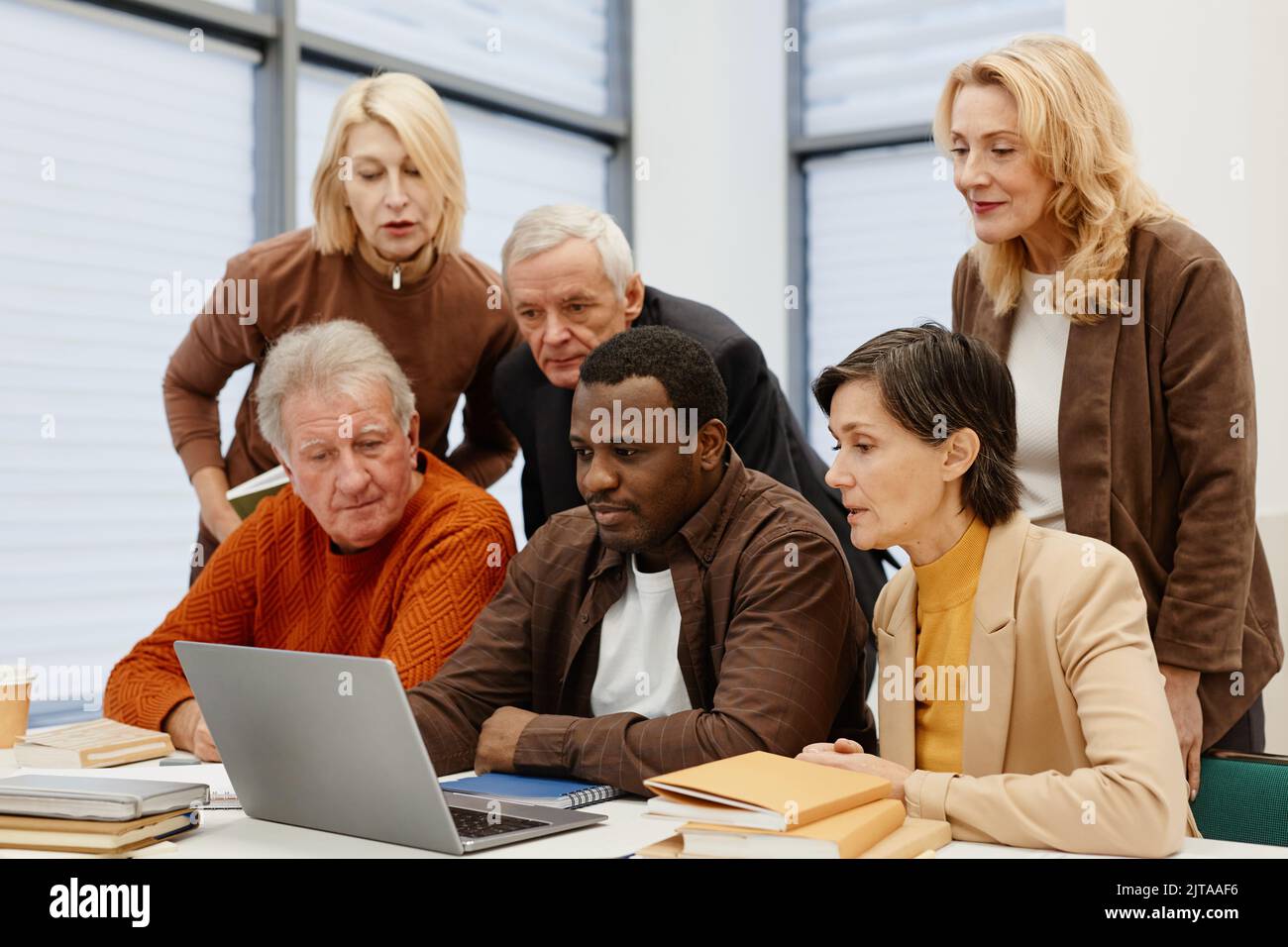 Group of senior people learning the basics of computer technology ...