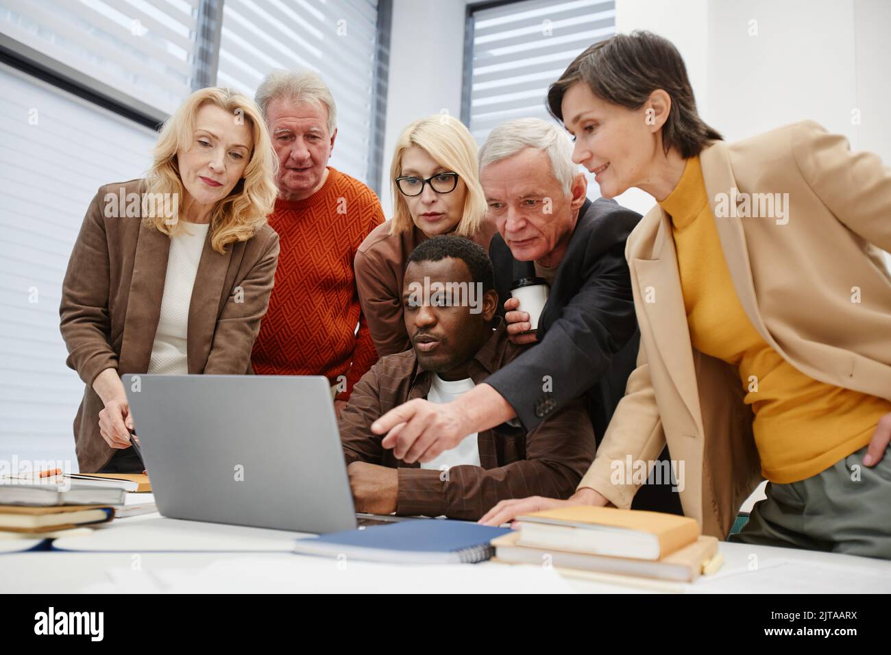 Group of senior people learning new computer program on laptop together ...