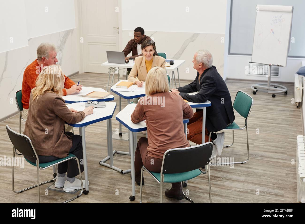 Group of students sitting at desks and working in team during lesson in ...