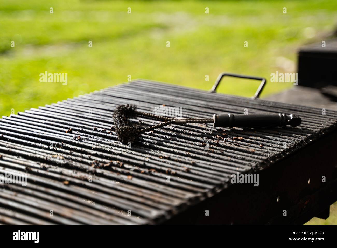 front view closeup of outdoor empty barbeque grill with black brush ...