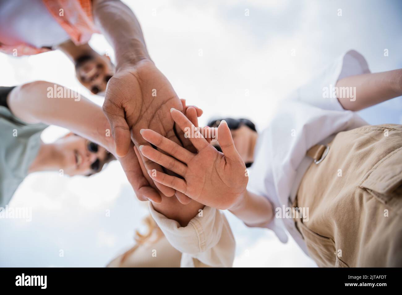 bottom view of multicultural people joining hands as sign of friendship ...