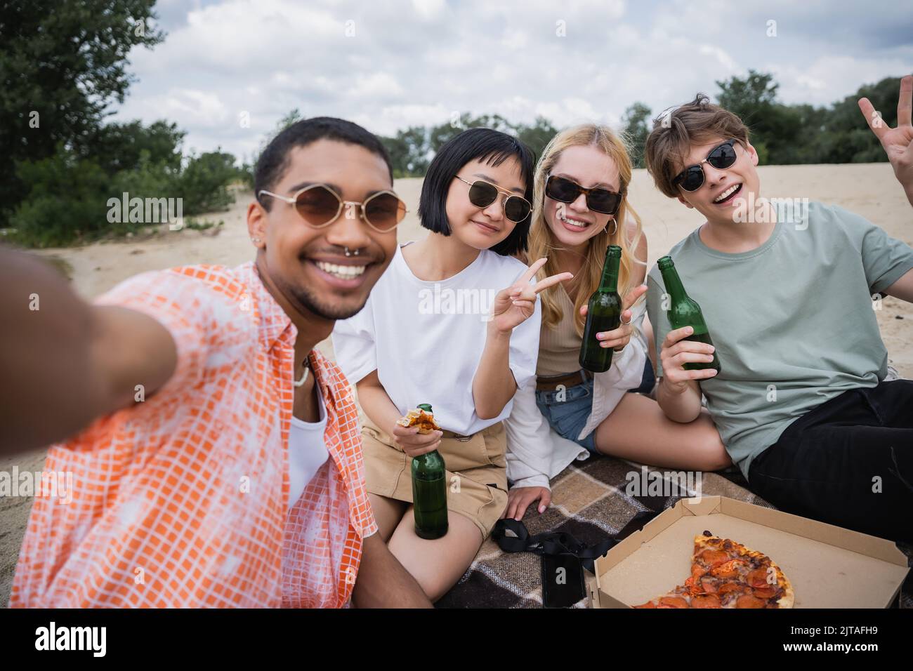 happy multiethnic friends looking at camera and showing peace signs ...