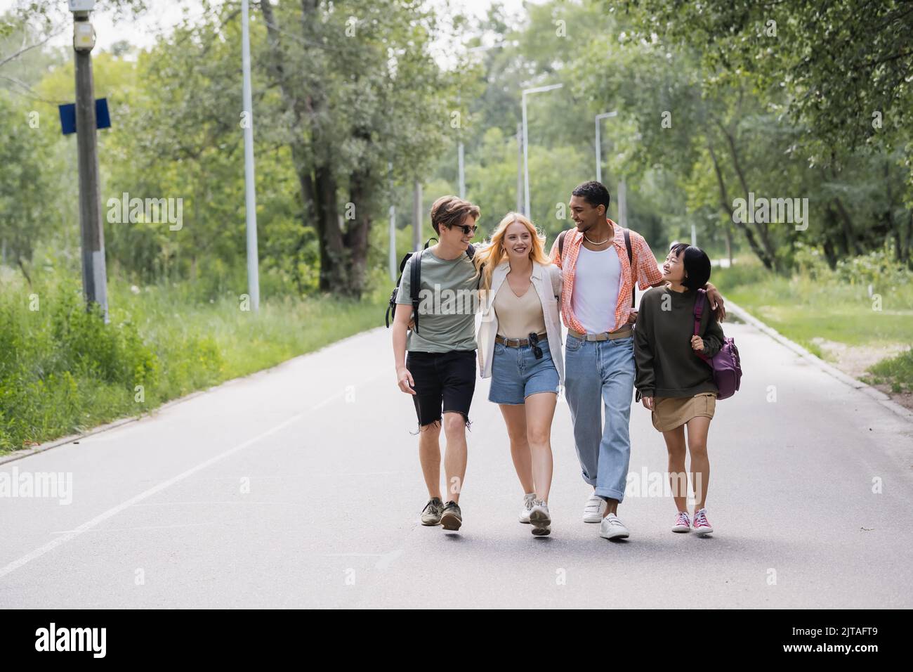 full length of multicultural tourists embracing while walking on ...