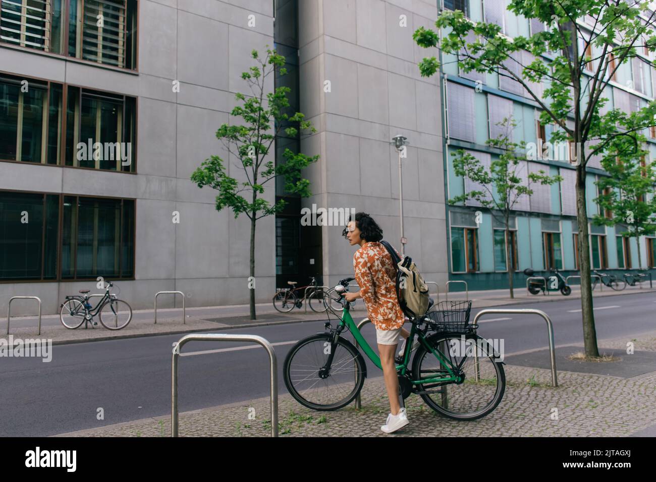 full length of amazed young woman in summer outfit riding bicycle in ...