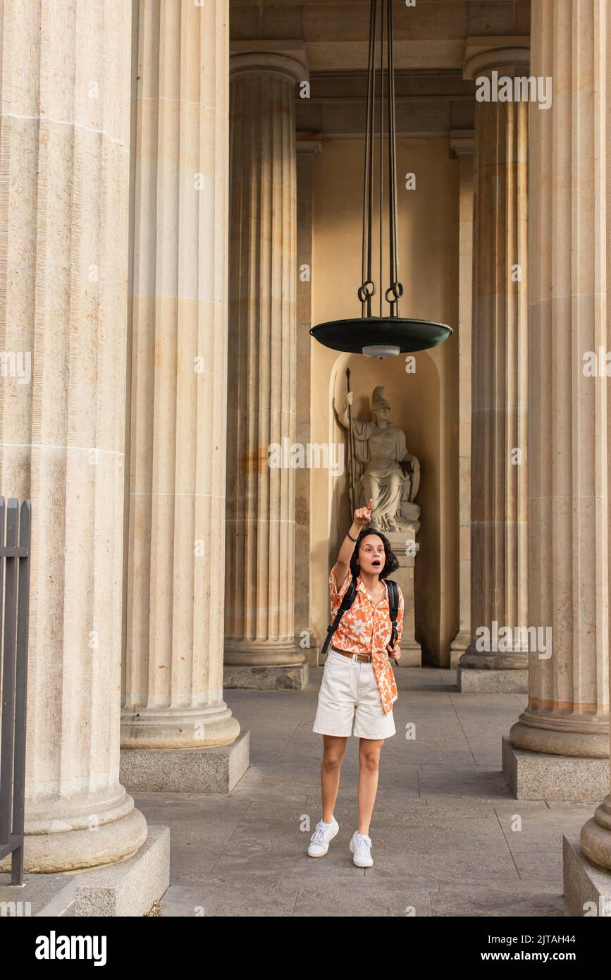 shocked traveler with backpack standing near ancient columns and statue ...