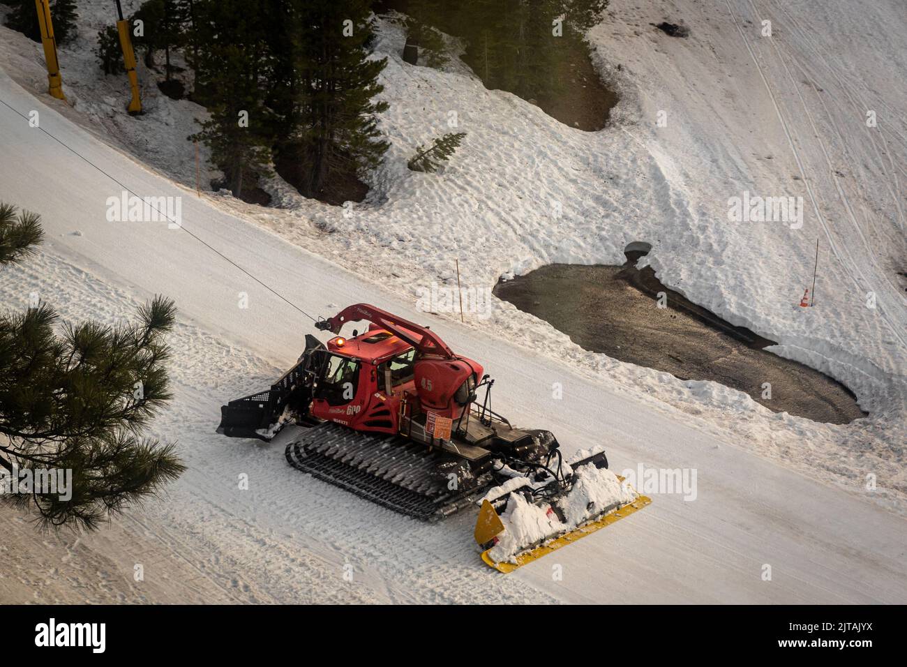A snowcat getting winched up a steep slope at a mountain Stock Photo ...