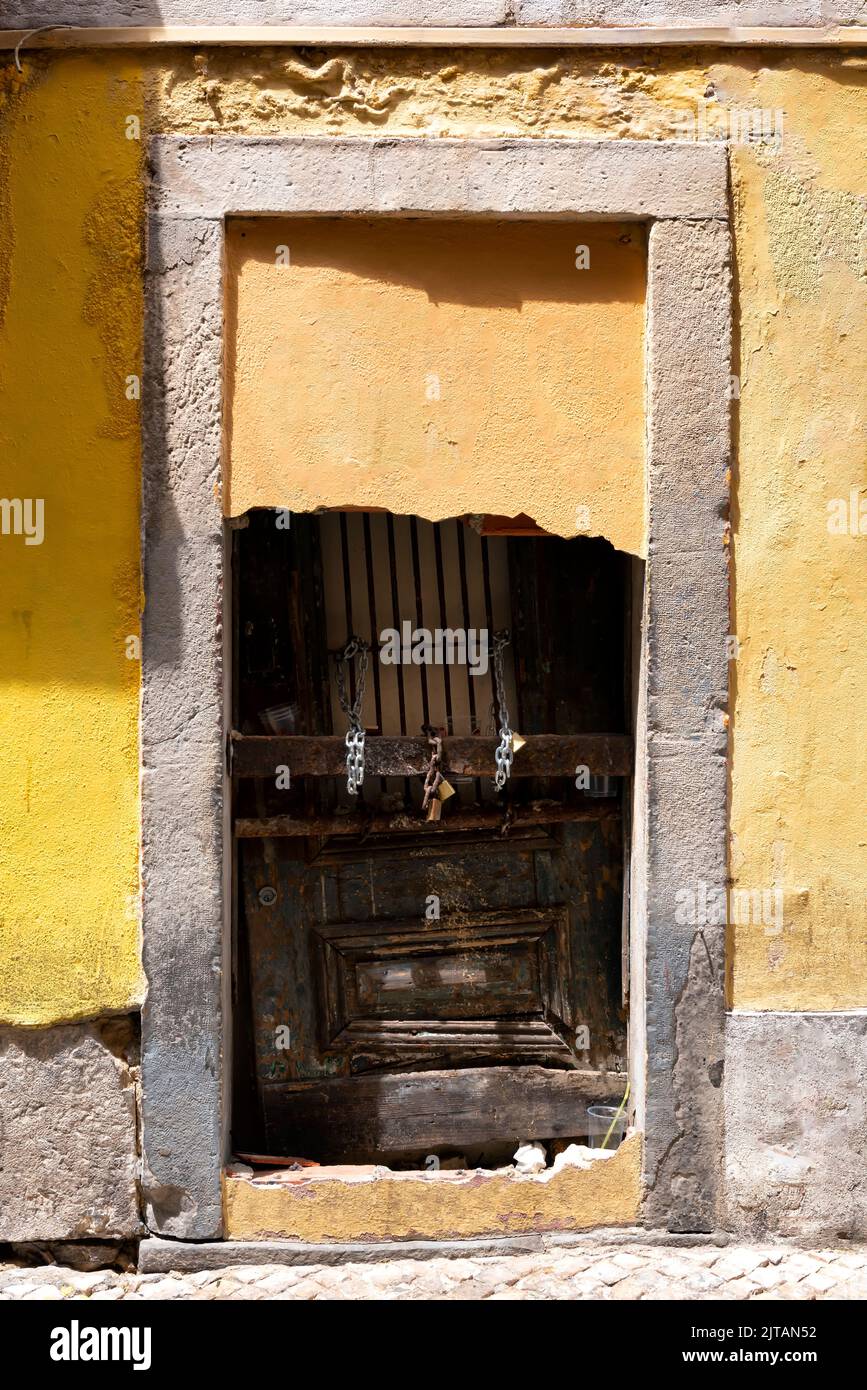 Partially covered entrance with old door chained to bar Stock Photo - Alamy