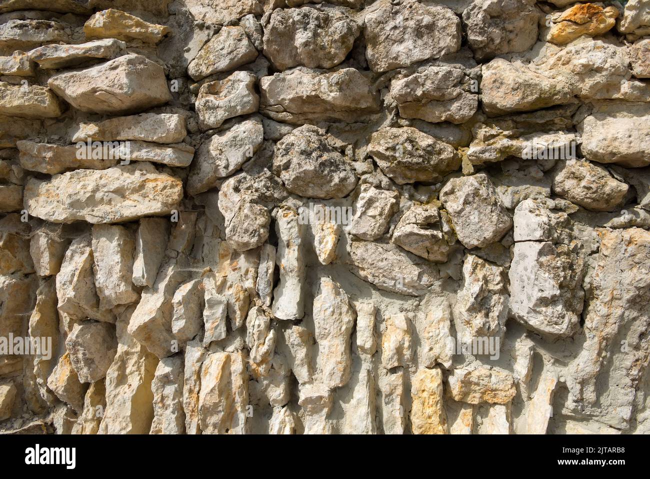 Natural stack rock stone wall building facade with deep shadows in ...