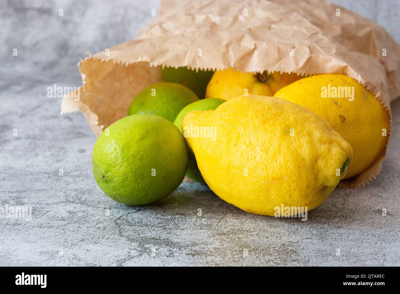 Lemon and lime in a brown paper bag on a concrete background. Eco ...