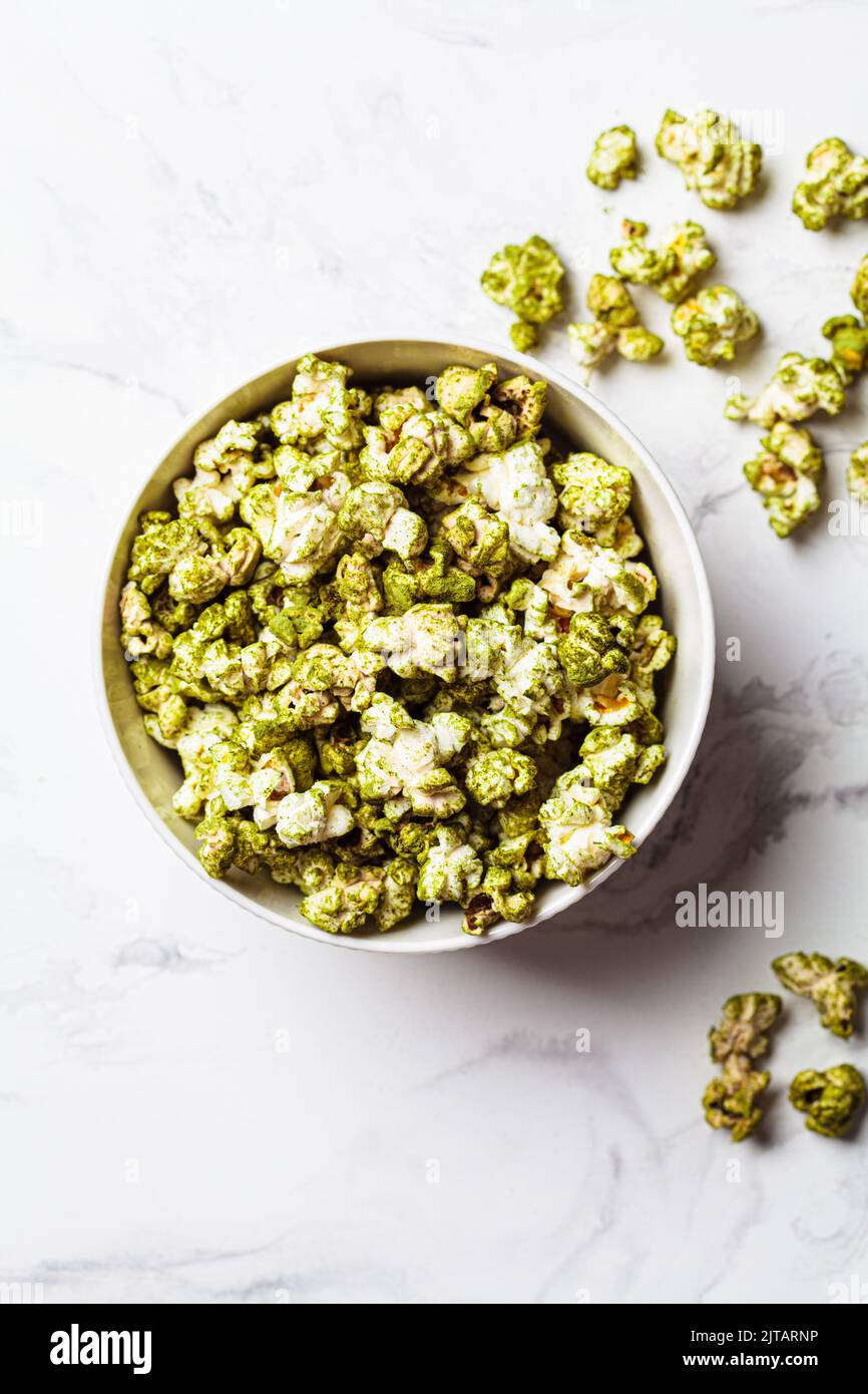 Vegan green matcha popcorn in a white bowl, top view. Alternative food ...