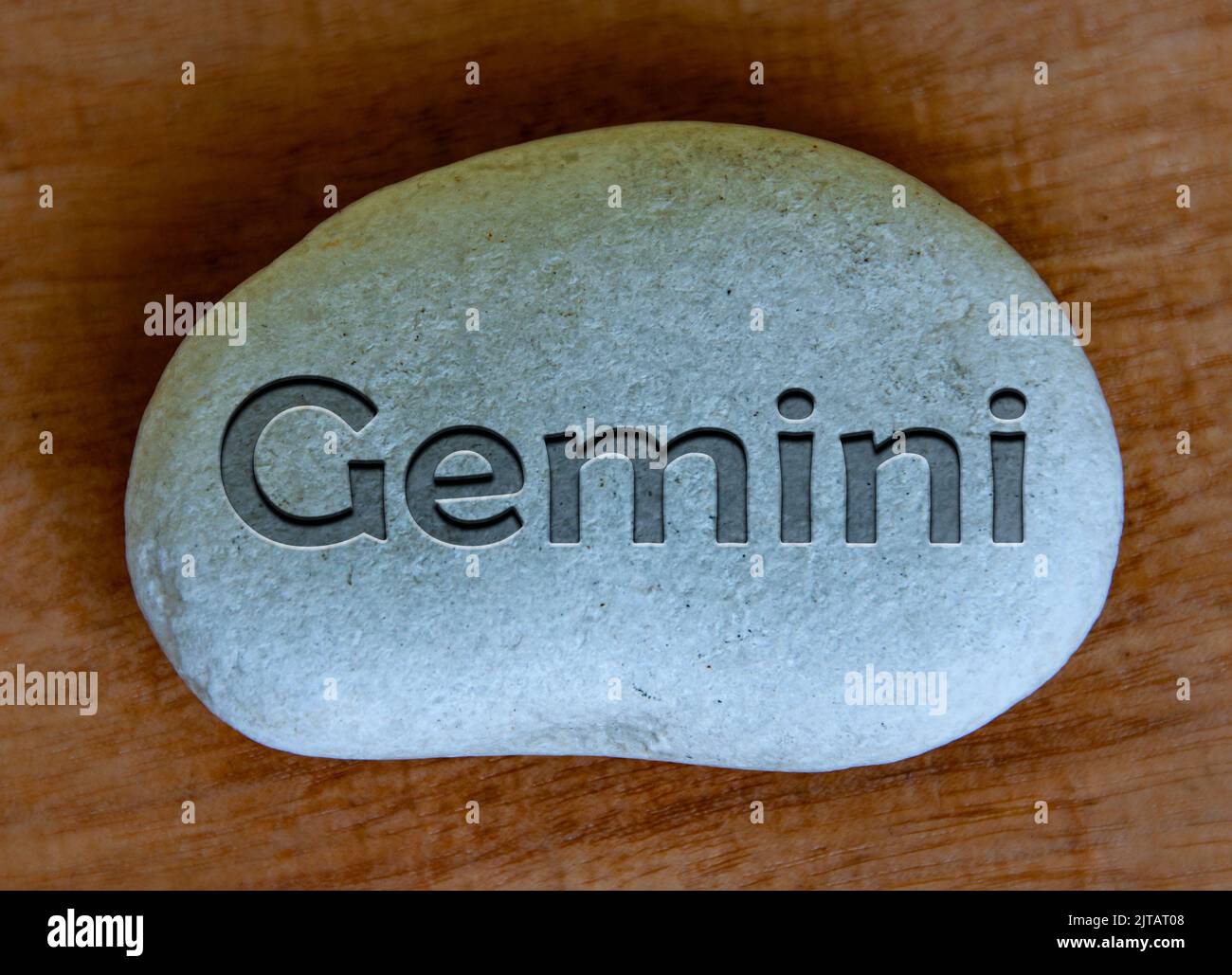 Gemini zodiac sign text engraved on a stock with wooden background ...