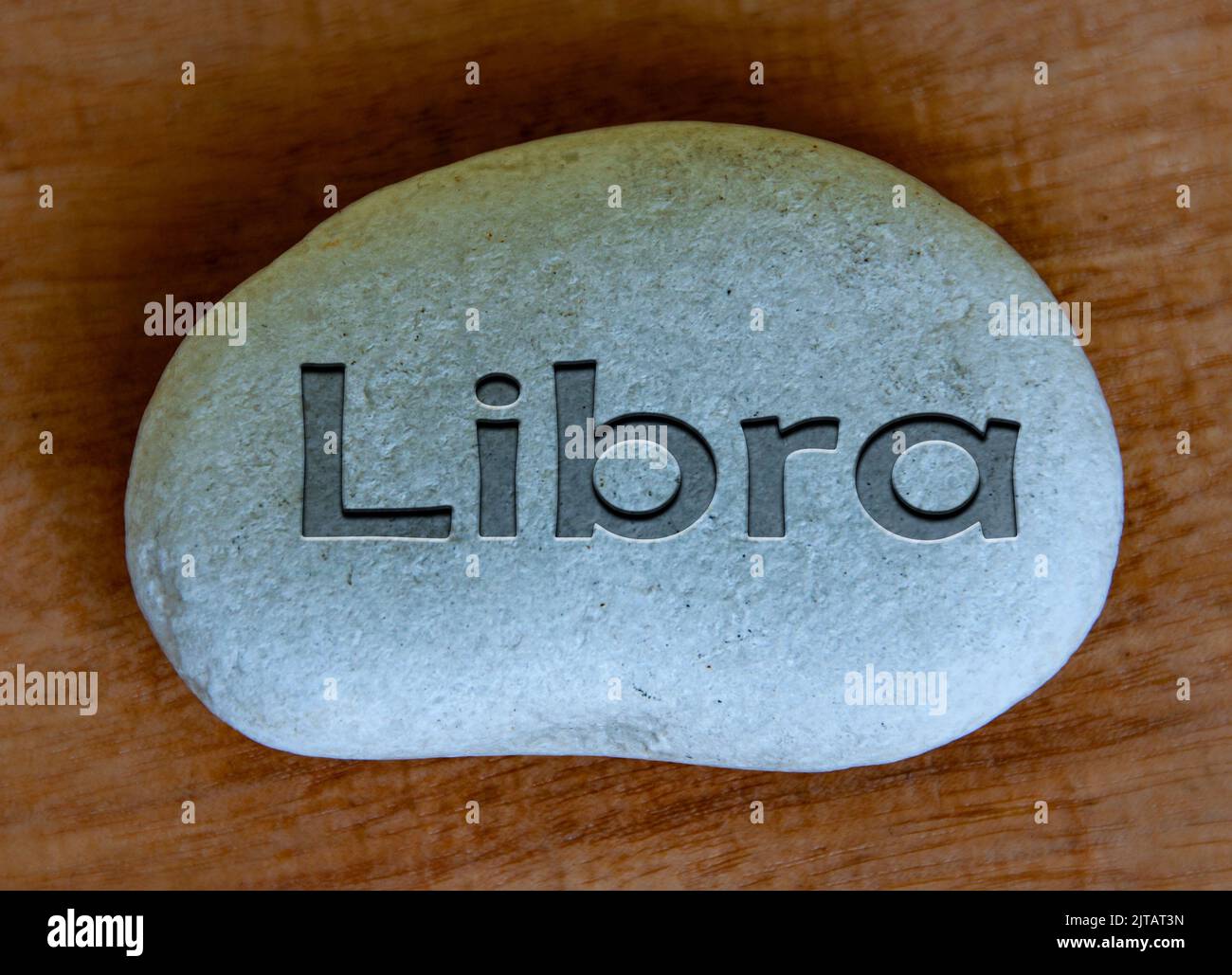 Libra zodiac sign text engraved on a stock with wooden background ...