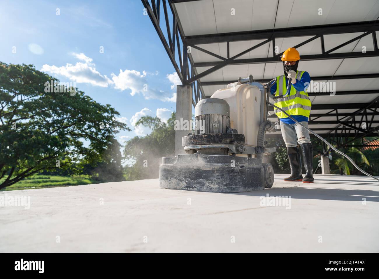 A worker trowelling with power tool on concrete surface at construction ...