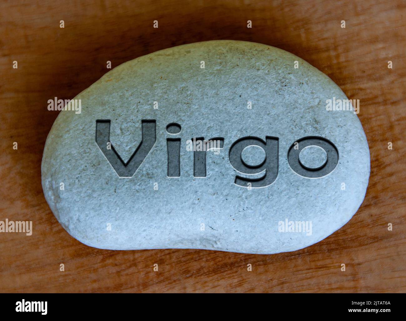 Virgo zodiac sign text engraved on a stock with wooden background ...