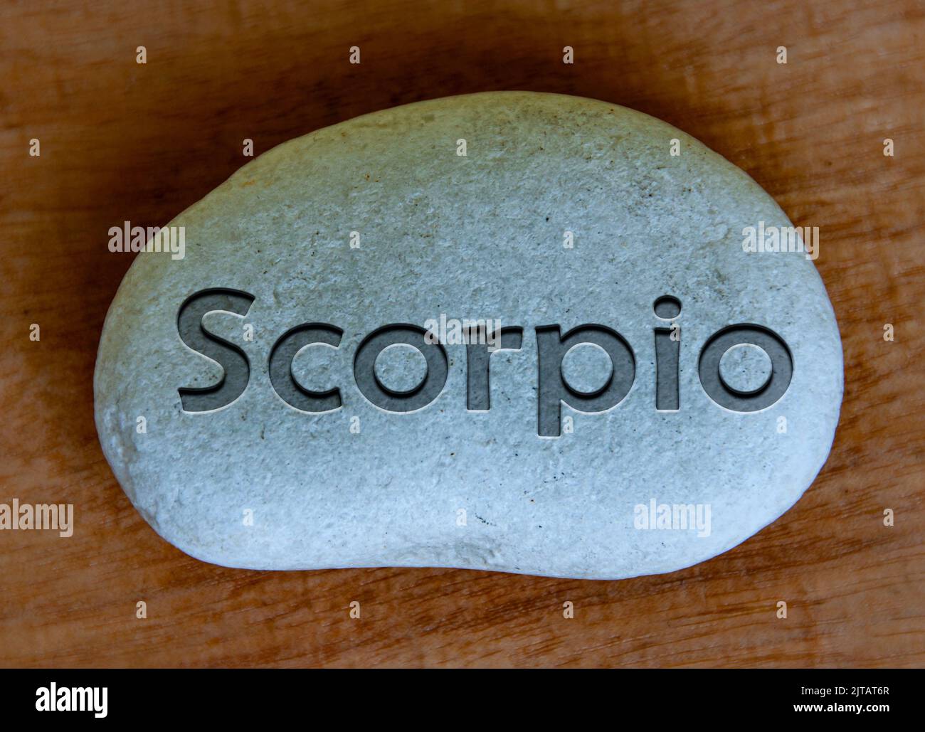 Scorpio zodiac sign text engraved on a stock with wooden background ...