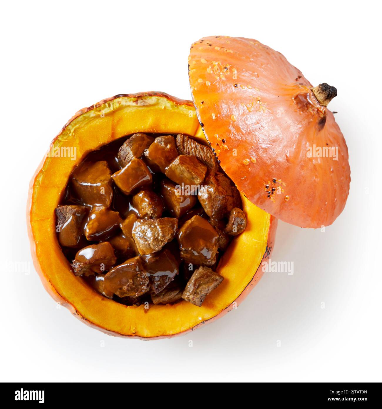 Top view of stewed pieces of meat served in small pumpkin on white ...