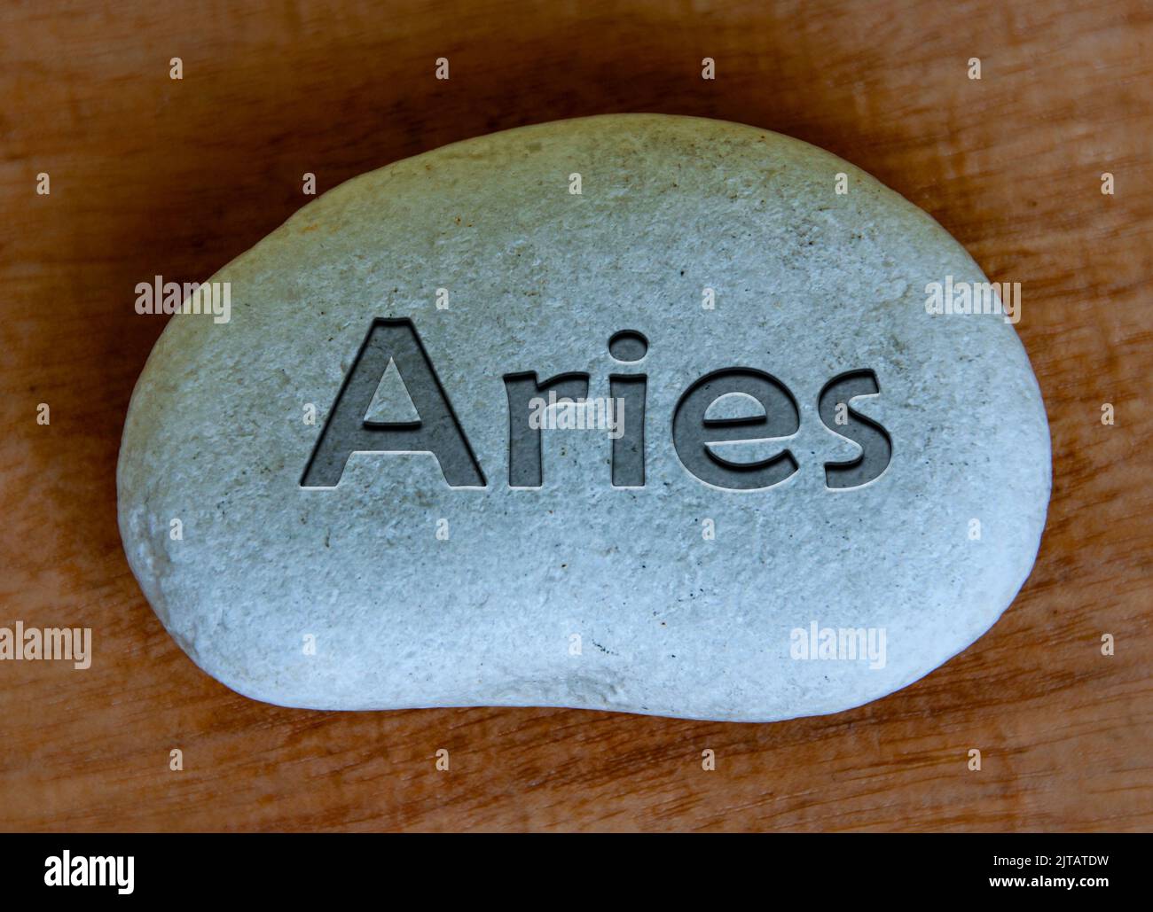 Aries zodiac sign text engraved on a stock with wooden background ...