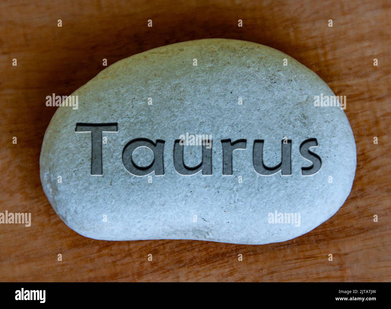 Taurus zodiac sign text engraved on a stock with wooden background ...