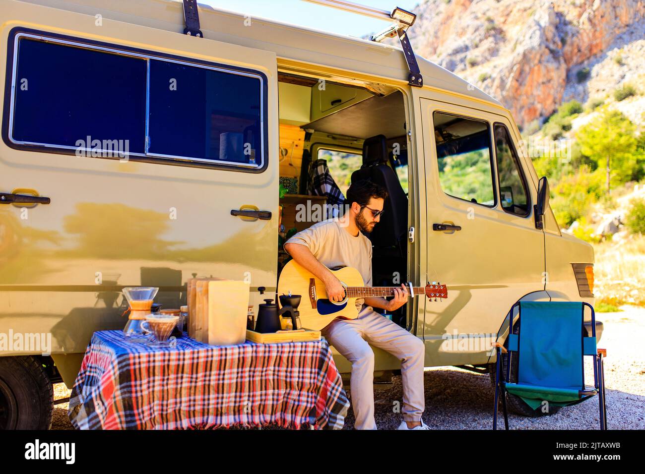 young man relaxing in rv, camping in a trailer mountain background ...