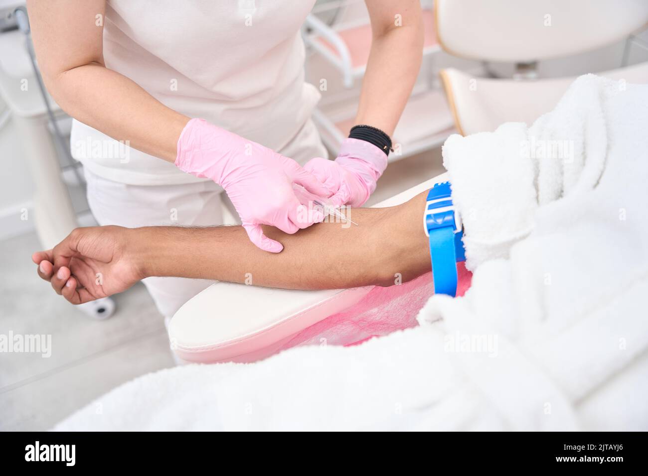 Experienced phlebotomist performing venipuncture procedure in clinic ...