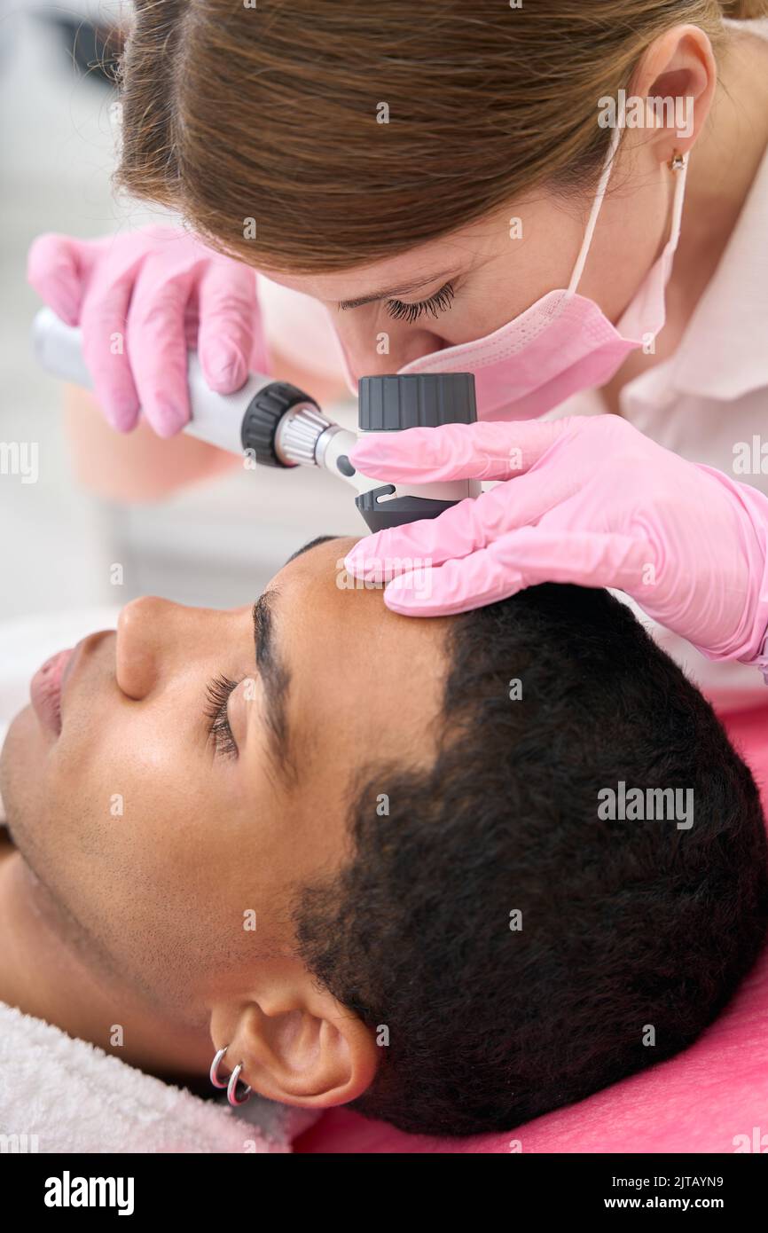 Qualified female doctor carrying out dermatoscopy procedure Stock Photo ...
