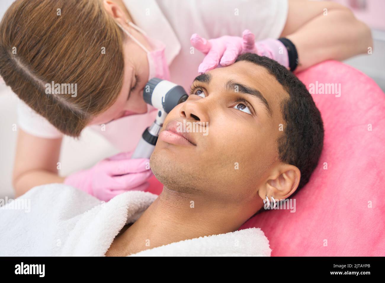 Dermatologist examining young man facial skin with dermatoscopy device ...
