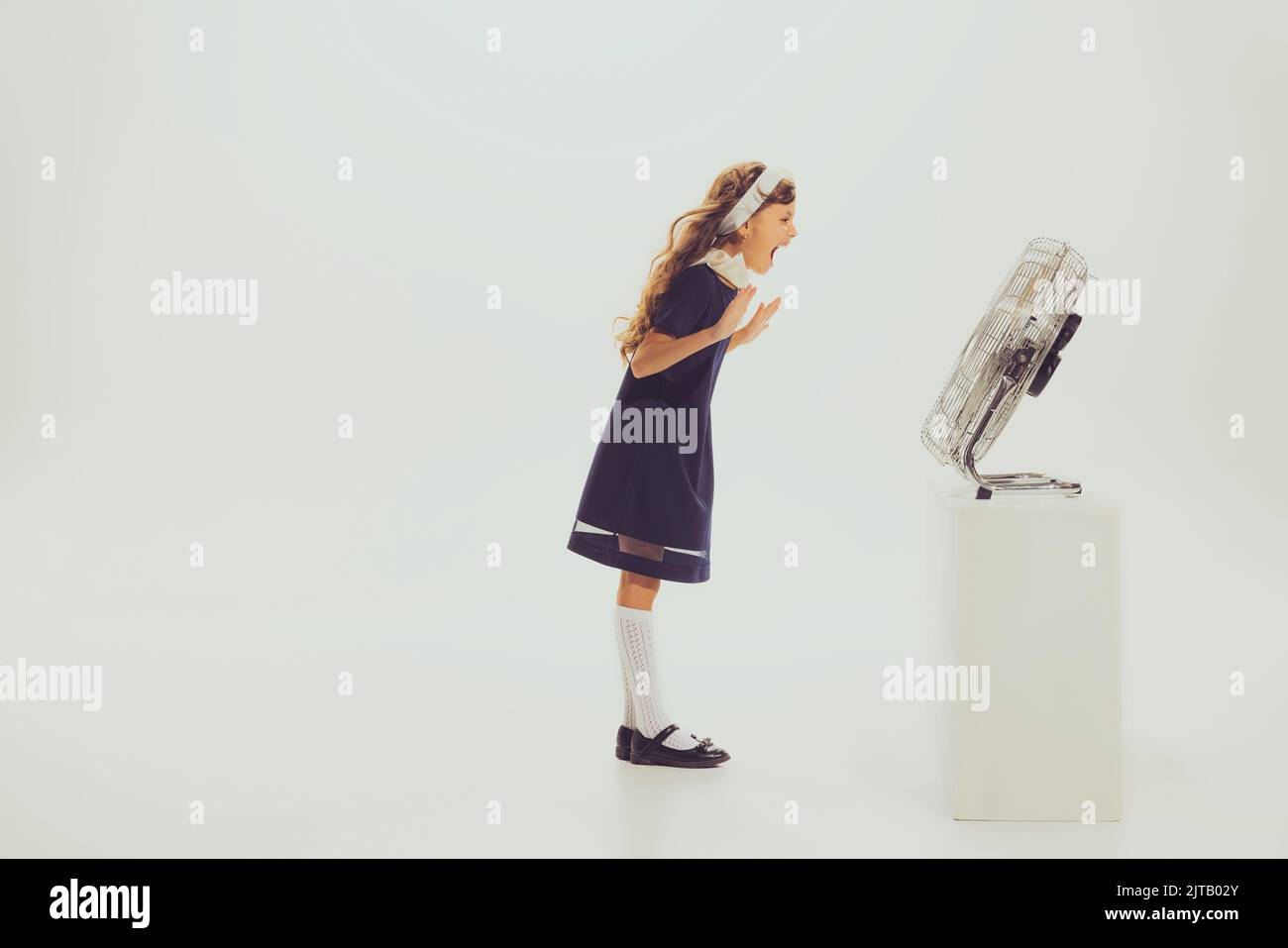 Portrait of little girl, child standing near fan and shouting isolated ...