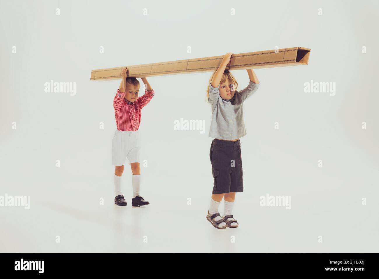 Portrait of two little boys, children carrying giant long box isolated ...