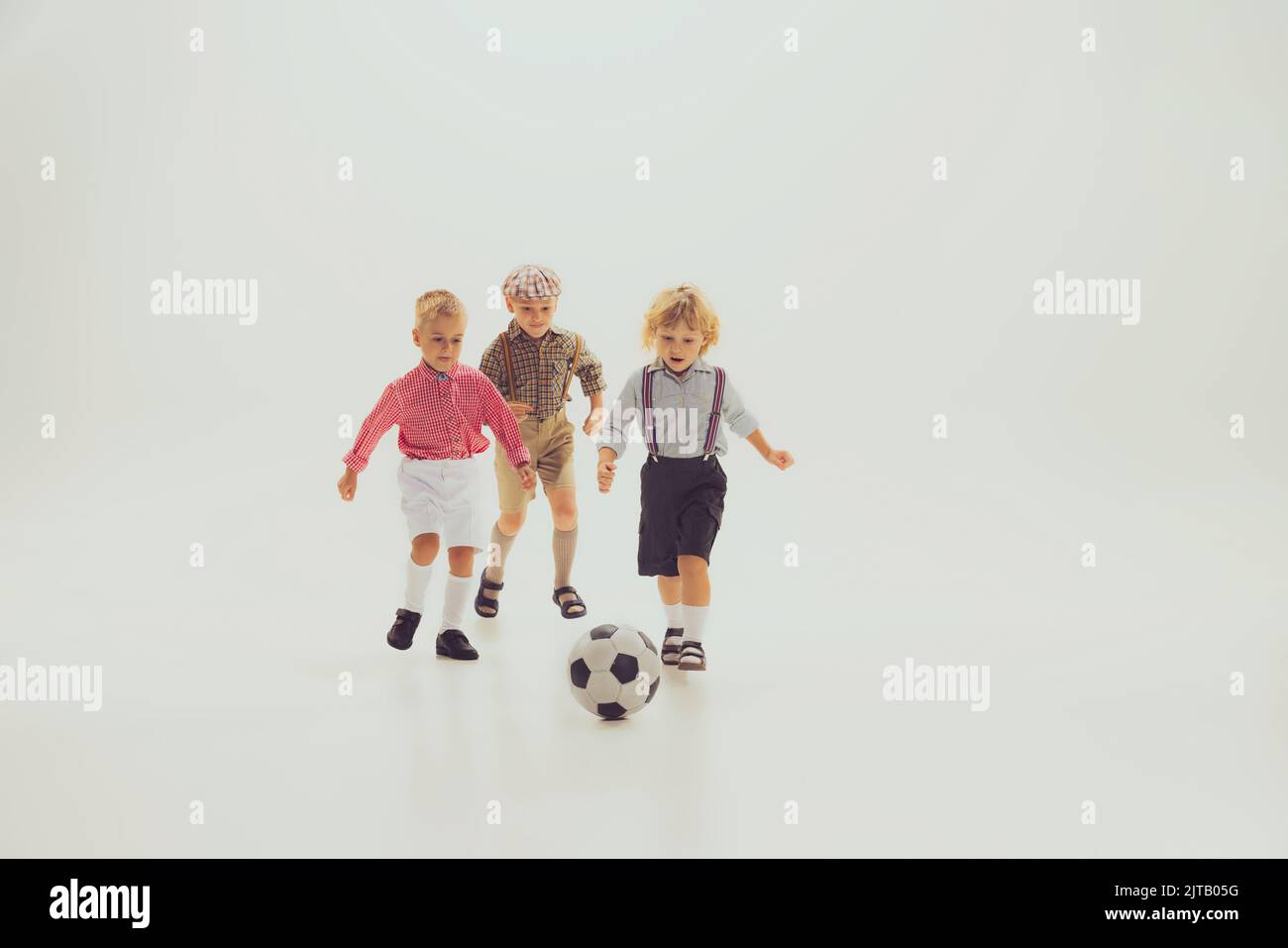 Portrait of little boys, children in vintage clothes playing football ...