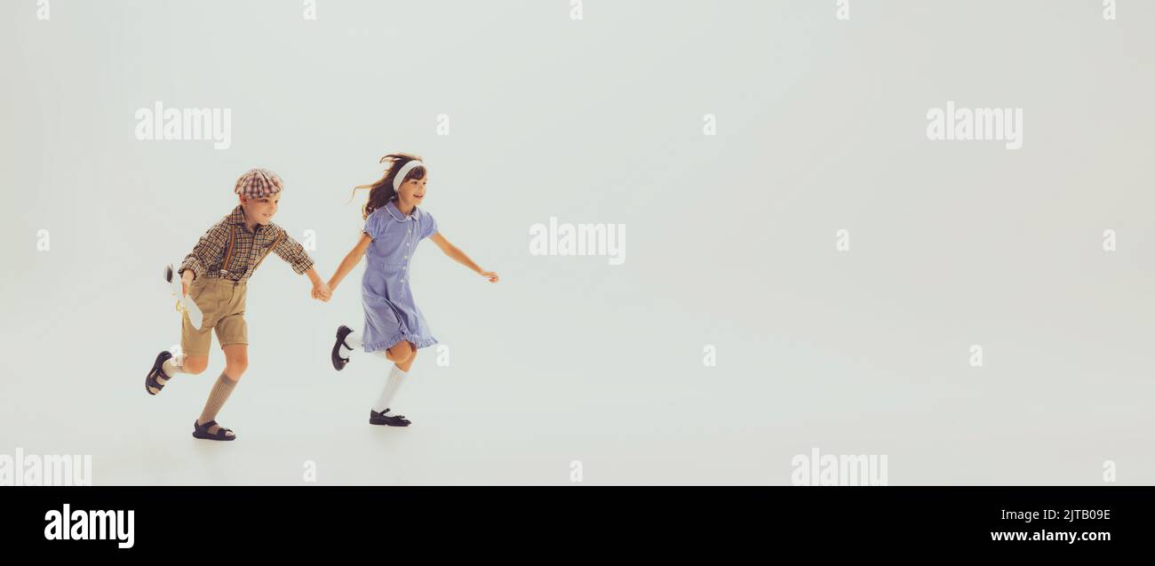 Portrait of stylish children, boy and girl, holding hands, running ...