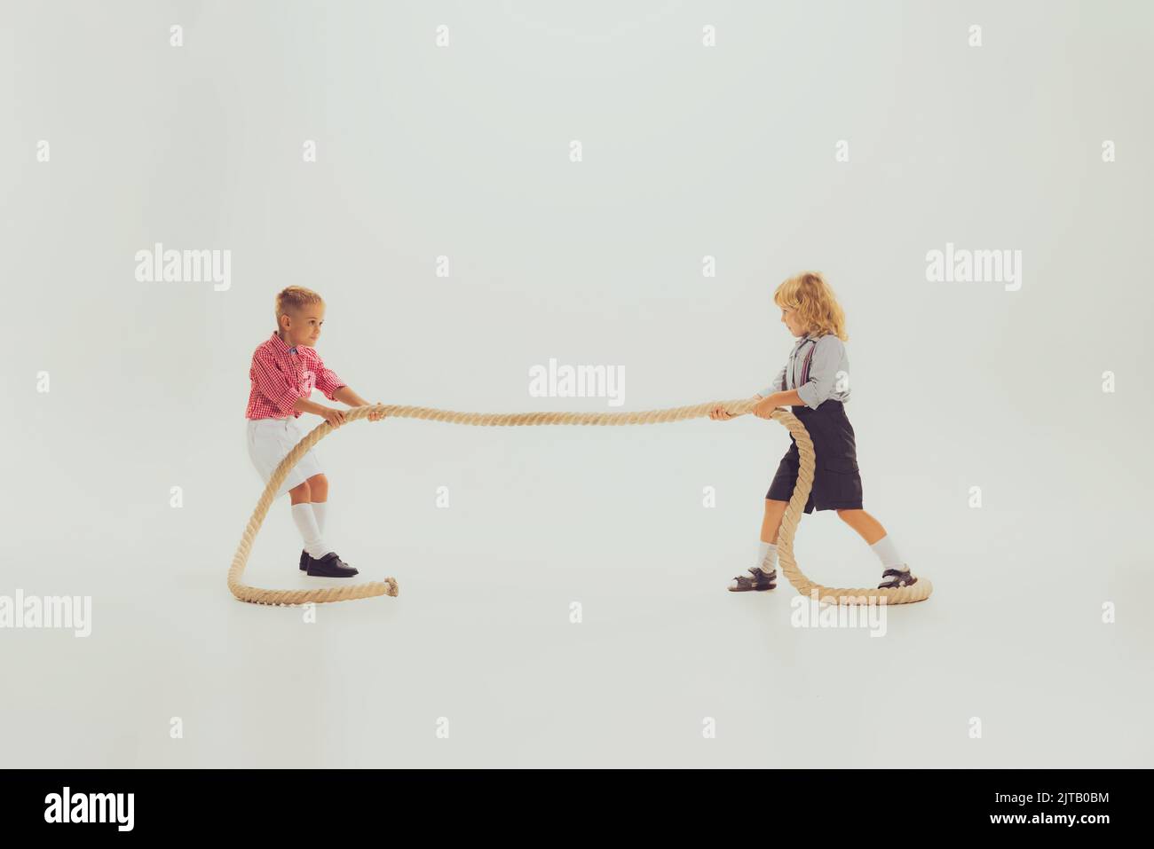 Portrait of two boys, children playing together, pulling the rope ...