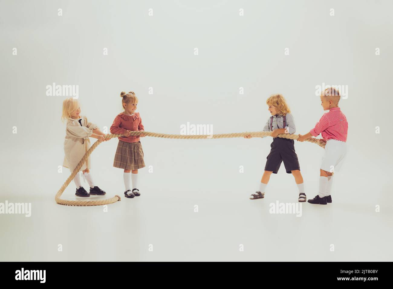 Portrait of children, boys and girls playing together, pulling the rope ...