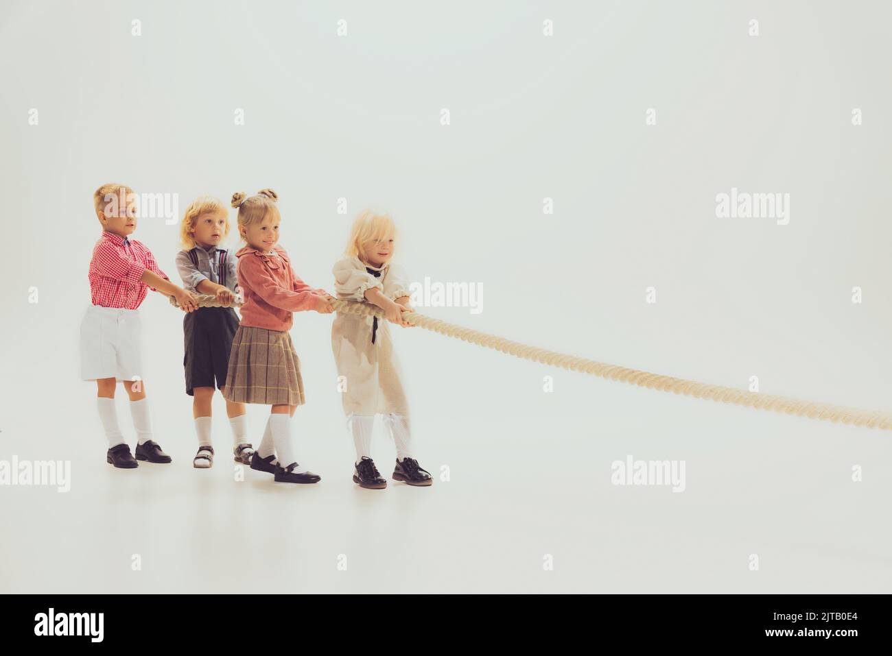 Portrait of children, boys and girls playing together, pulling the rope ...