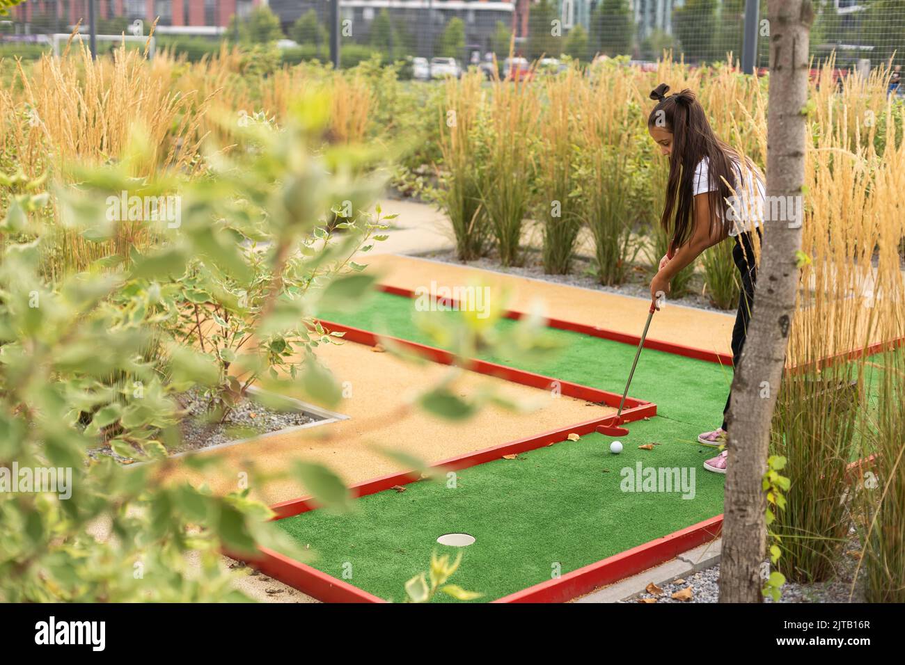 Cute little girl playing mini golf in a park Stock Photo - Alamy