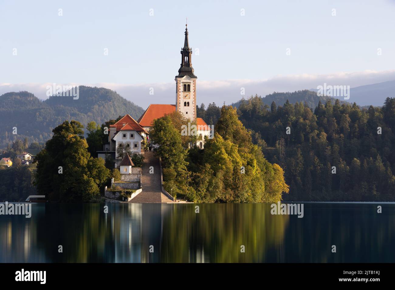 Church in Bled lake illuminated from side view at sunrise with clear ...