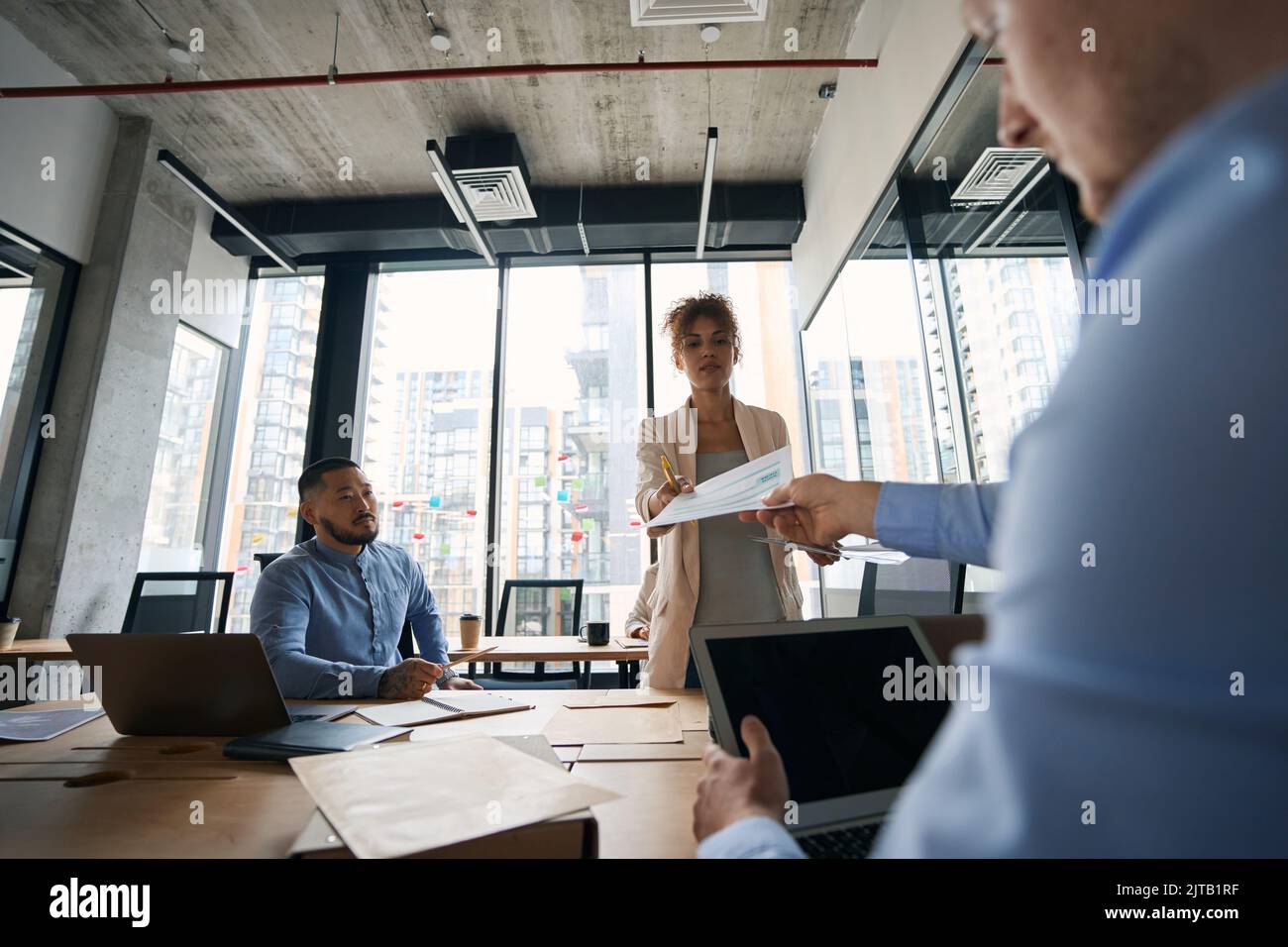 Serious young woman handing document to man at a meeting Stock Photo ...