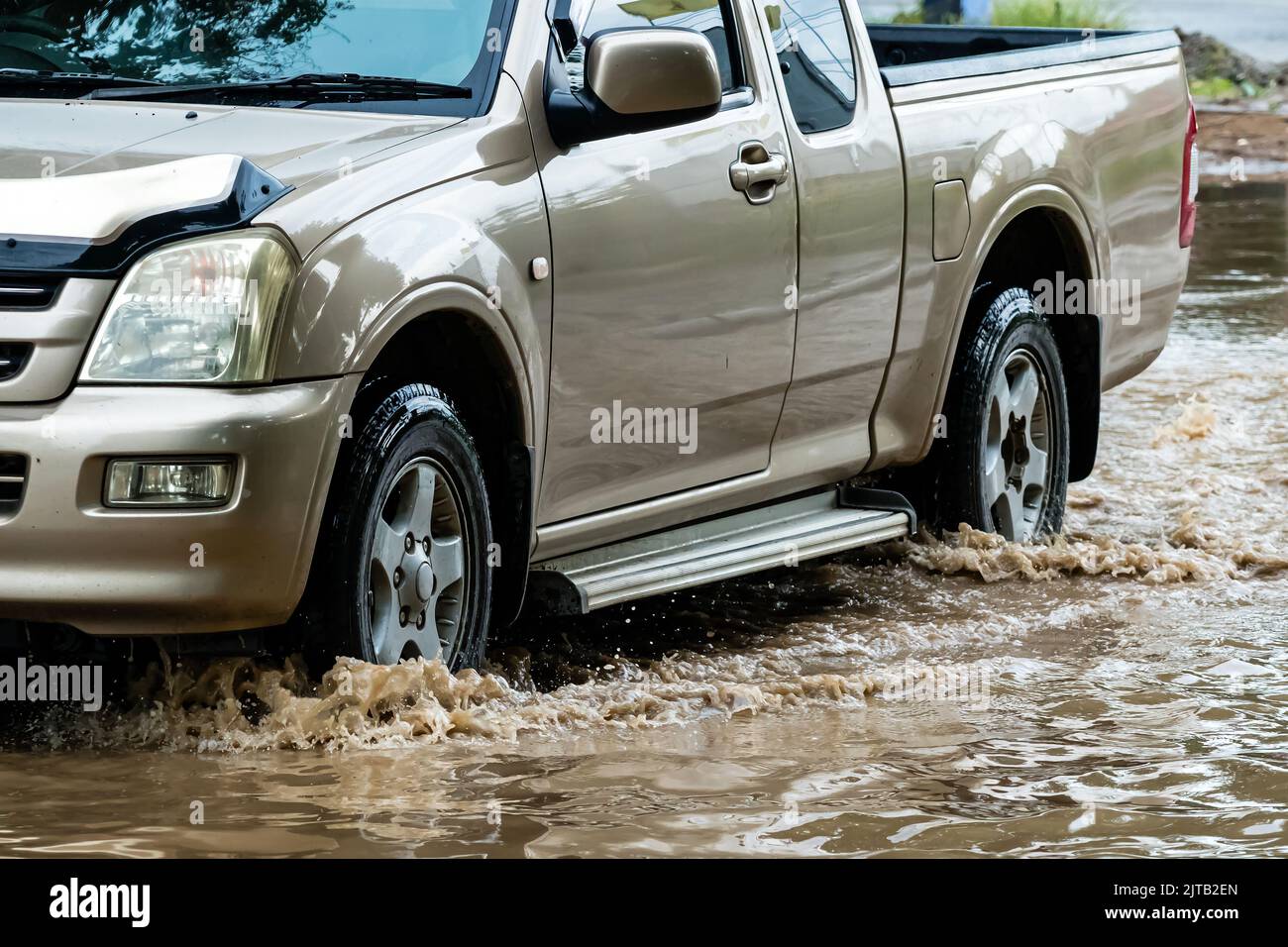 Pickup truck passing through flooded road. Driving car on flooded road during flood caused by ...