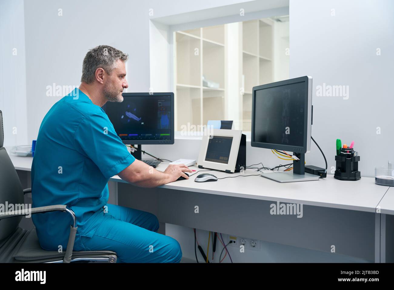 Man in blue medical overalls works at a table Stock Photo - Alamy