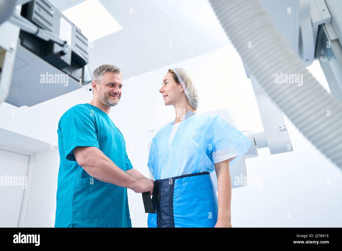 Radiologist at medical center putting lead shield on female patient ...